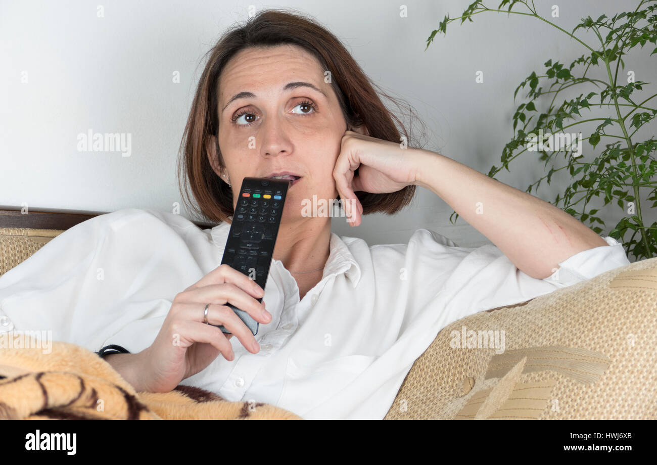 Young woman watching TV with remote in hands Stock Photo - Alamy