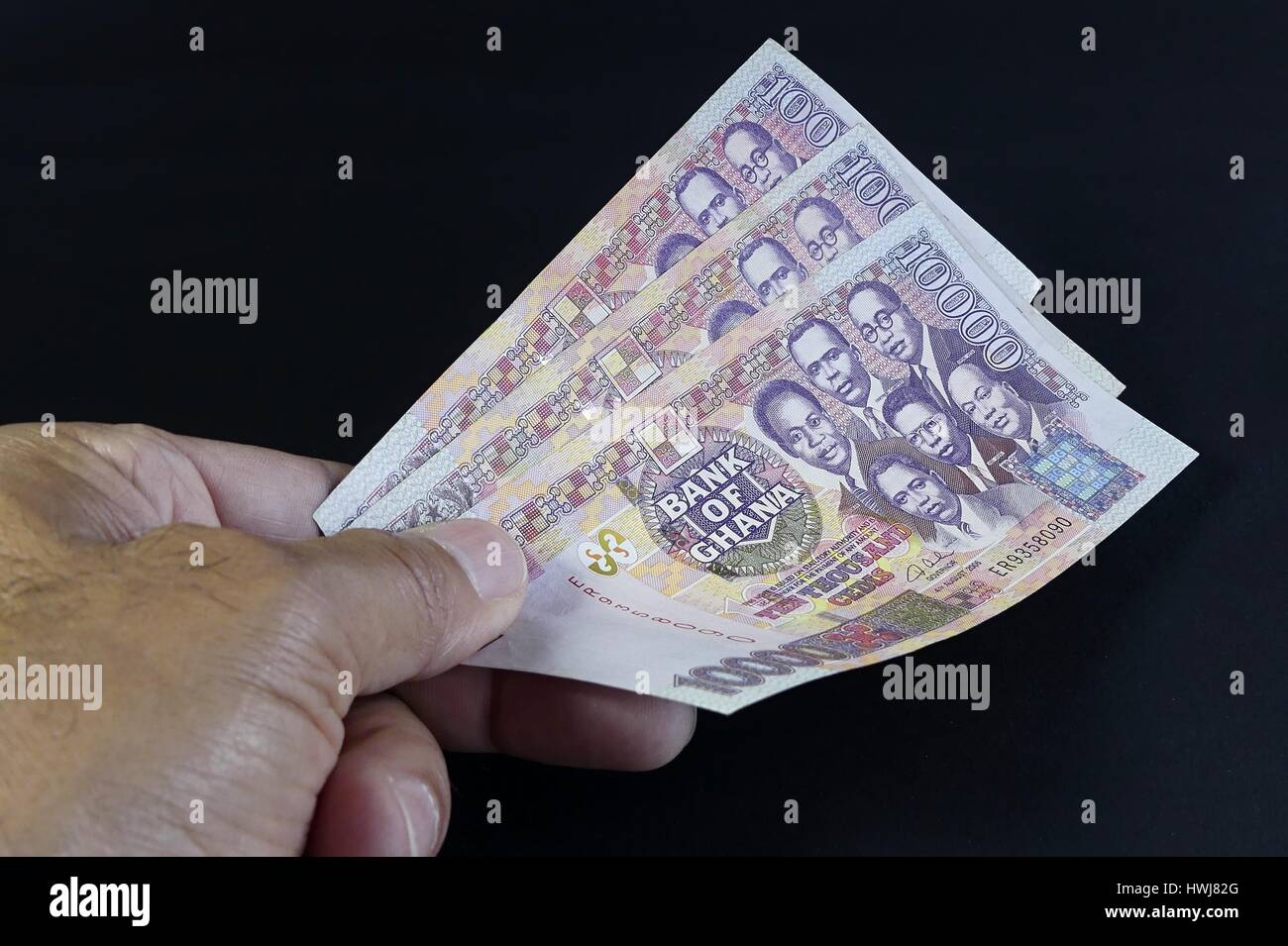 Hand handing Ghana banknotes isolated on black background Stock Photo ...