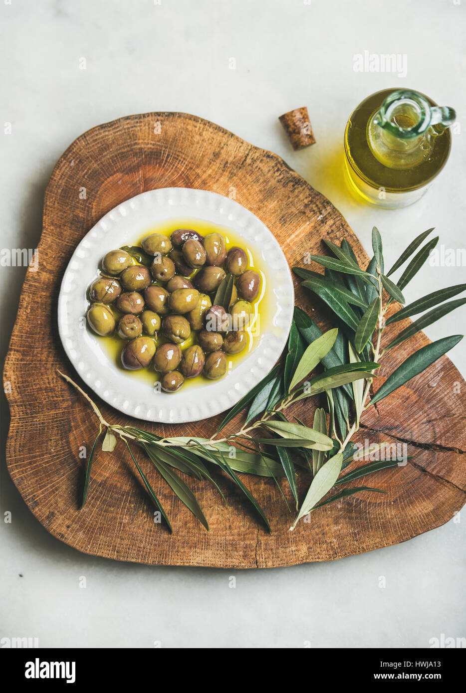 Pickled green Mediterranean olives and olive tree branch on wooden ...