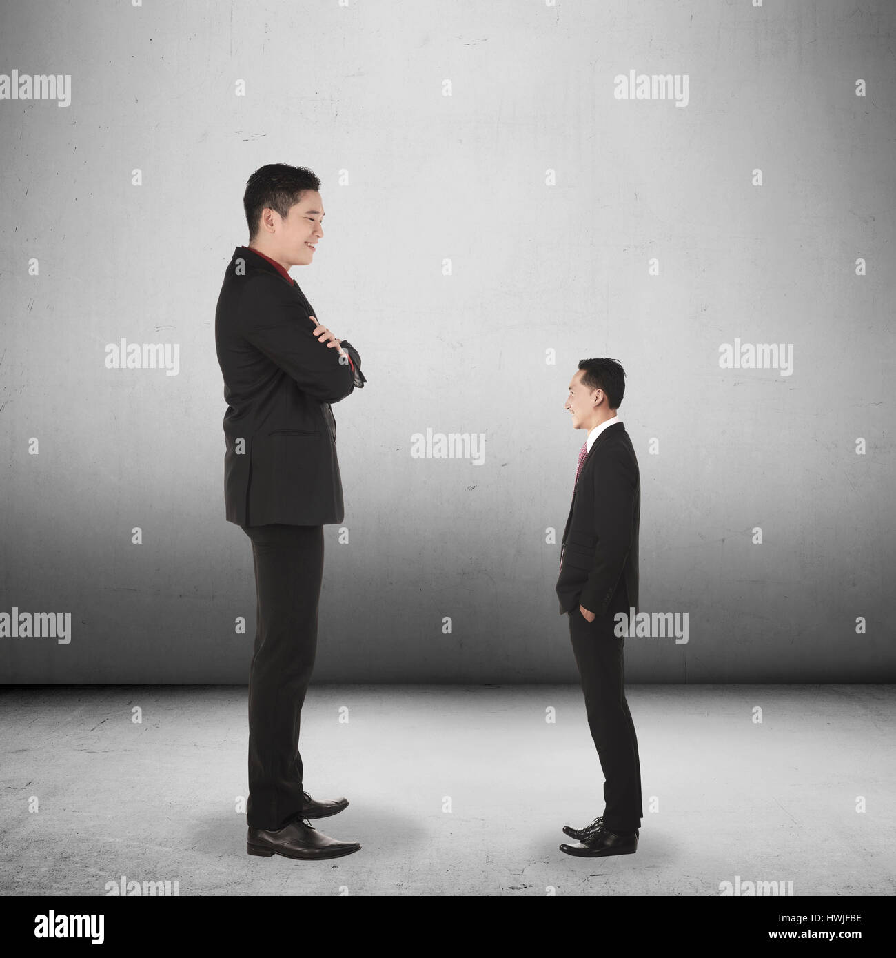 Small businessman looking at his big boss on grunge background Stock ...