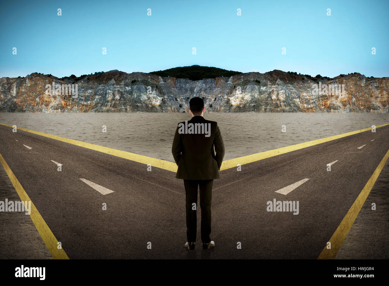 Asian man standing in the middle of cross road thinking about direction ...