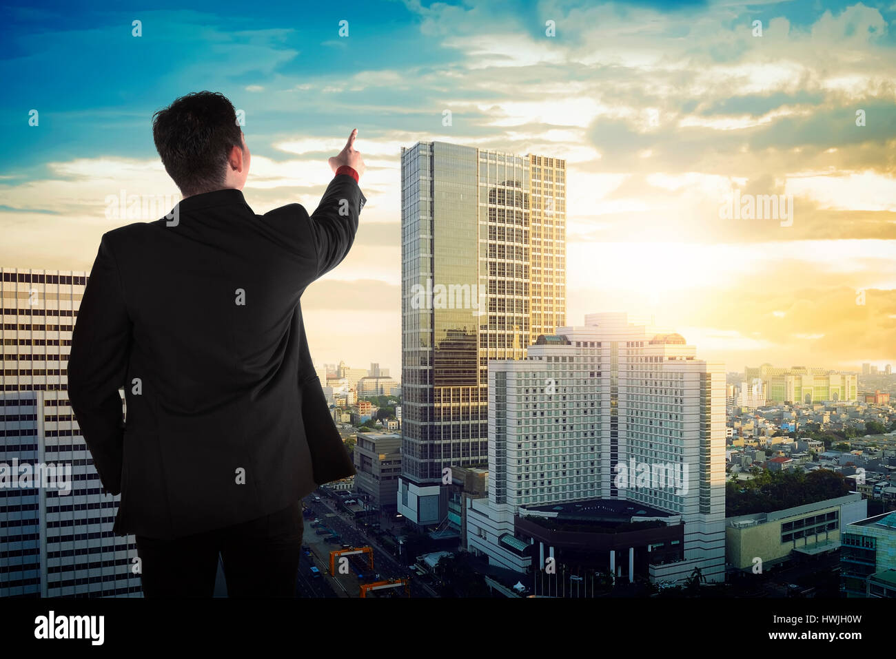 Back view of asian business man looking the sky on the building rooftop ...