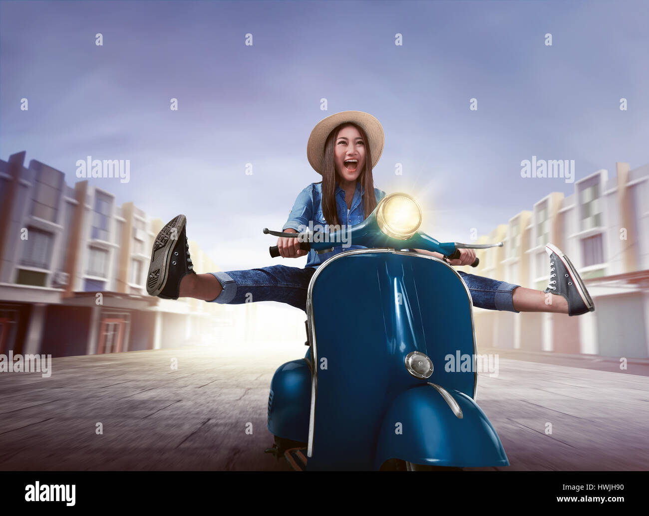 Beautiful happy asian woman riding a scooter raising both legs on the ...