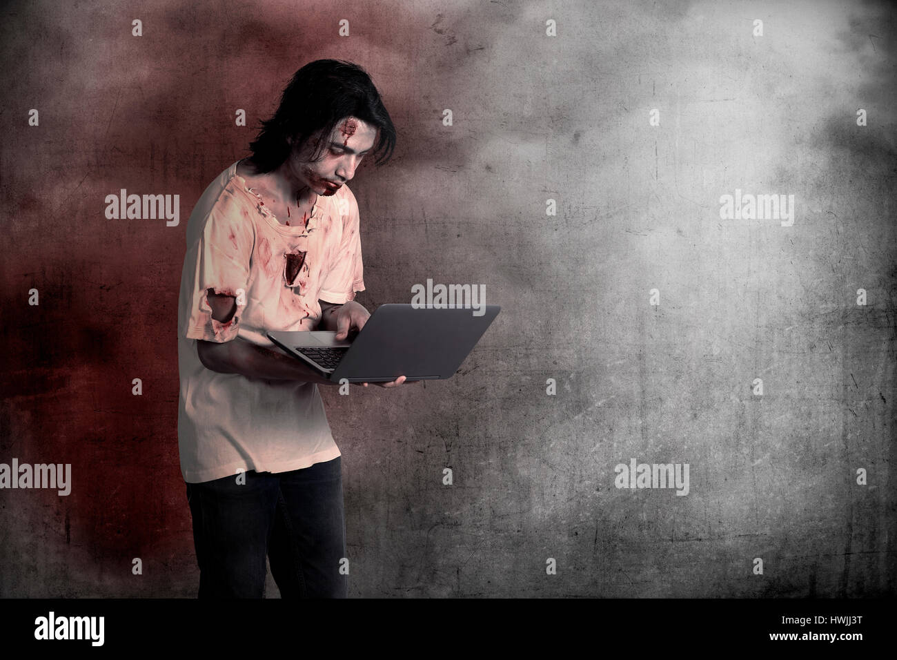 Scary male zombie typing with laptop over grunge background Stock Photo ...