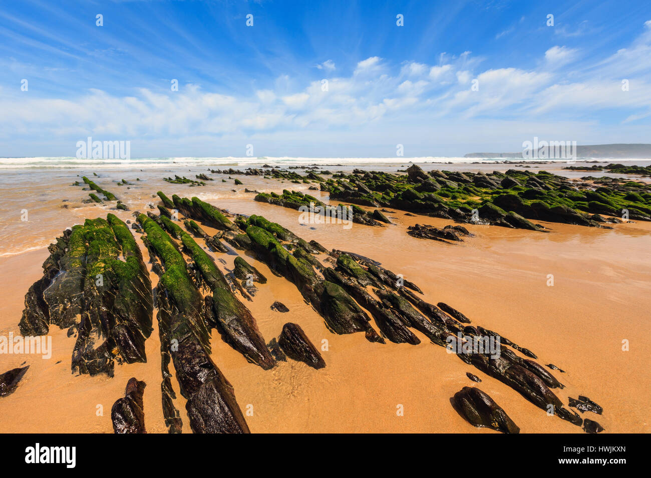 Rock formations on sandy beach and blue sky with cumulus clouds ...