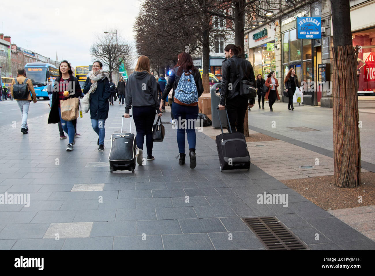 three tourists people walking along busy oconnell street footpath ...