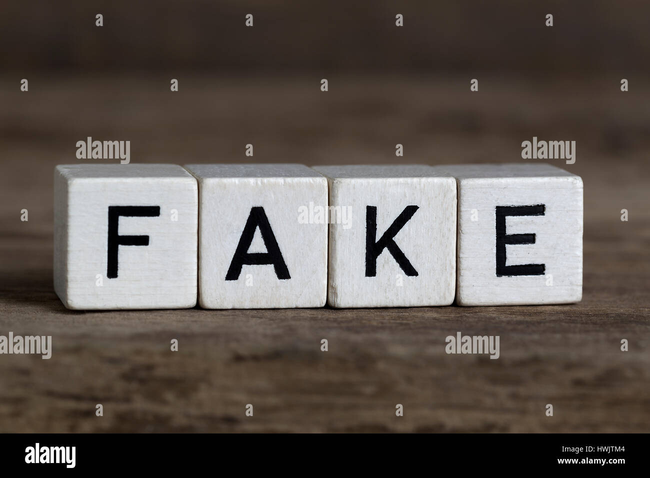 Fake, written in cubes on a wooden background Stock Photo - Alamy