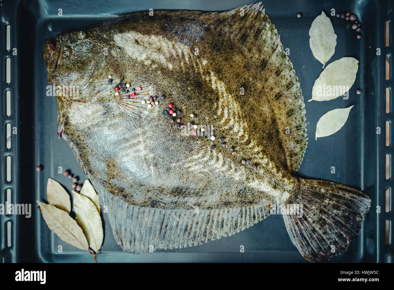 Fish flounder lies on a baking sheet decorated with spices Stock Photo ...
