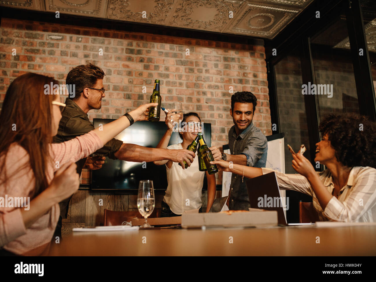 Group of young business professionals celebrating a success with beers ...