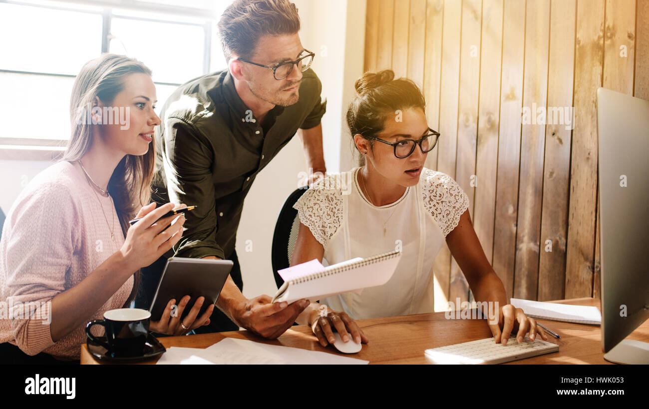 Shot of business team brainstorming while working on computer. Business ...