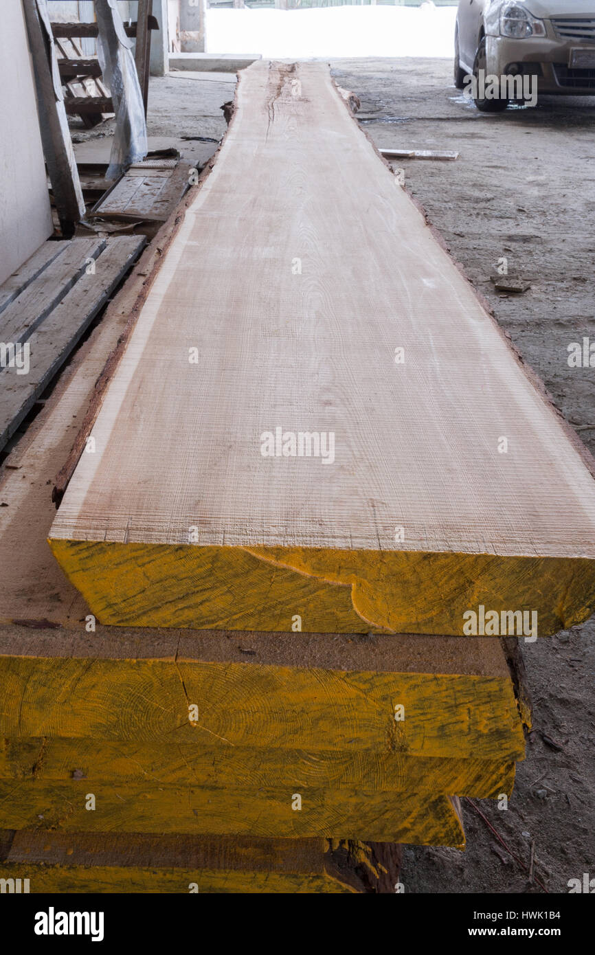 Stacked on top of each other larch slabs with bark and yellow colored ...