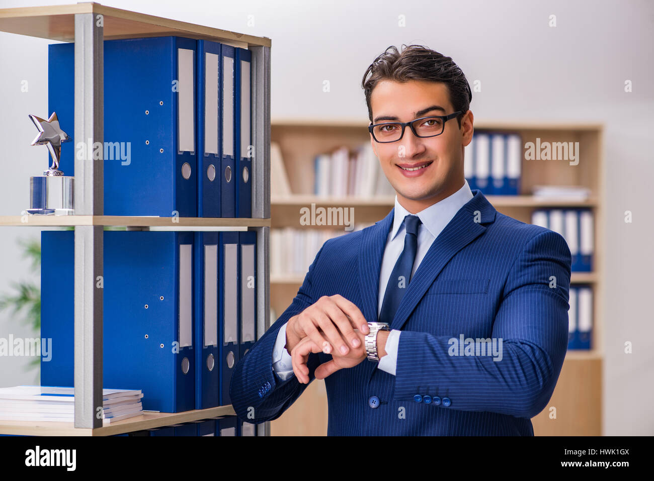 Young man standing next to the shelf with folders Stock Photo - Alamy