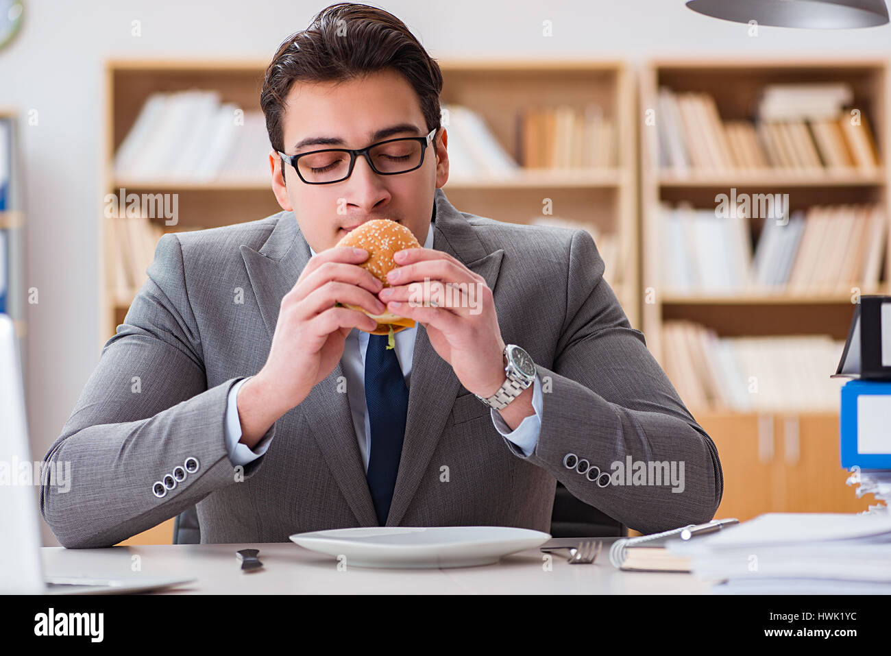 Hungry funny businessman eating junk food sandwich Stock Photo - Alamy
