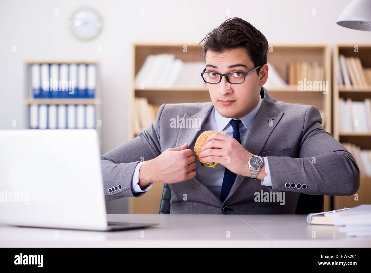 Hungry funny businessman eating junk food sandwich Stock Photo - Alamy