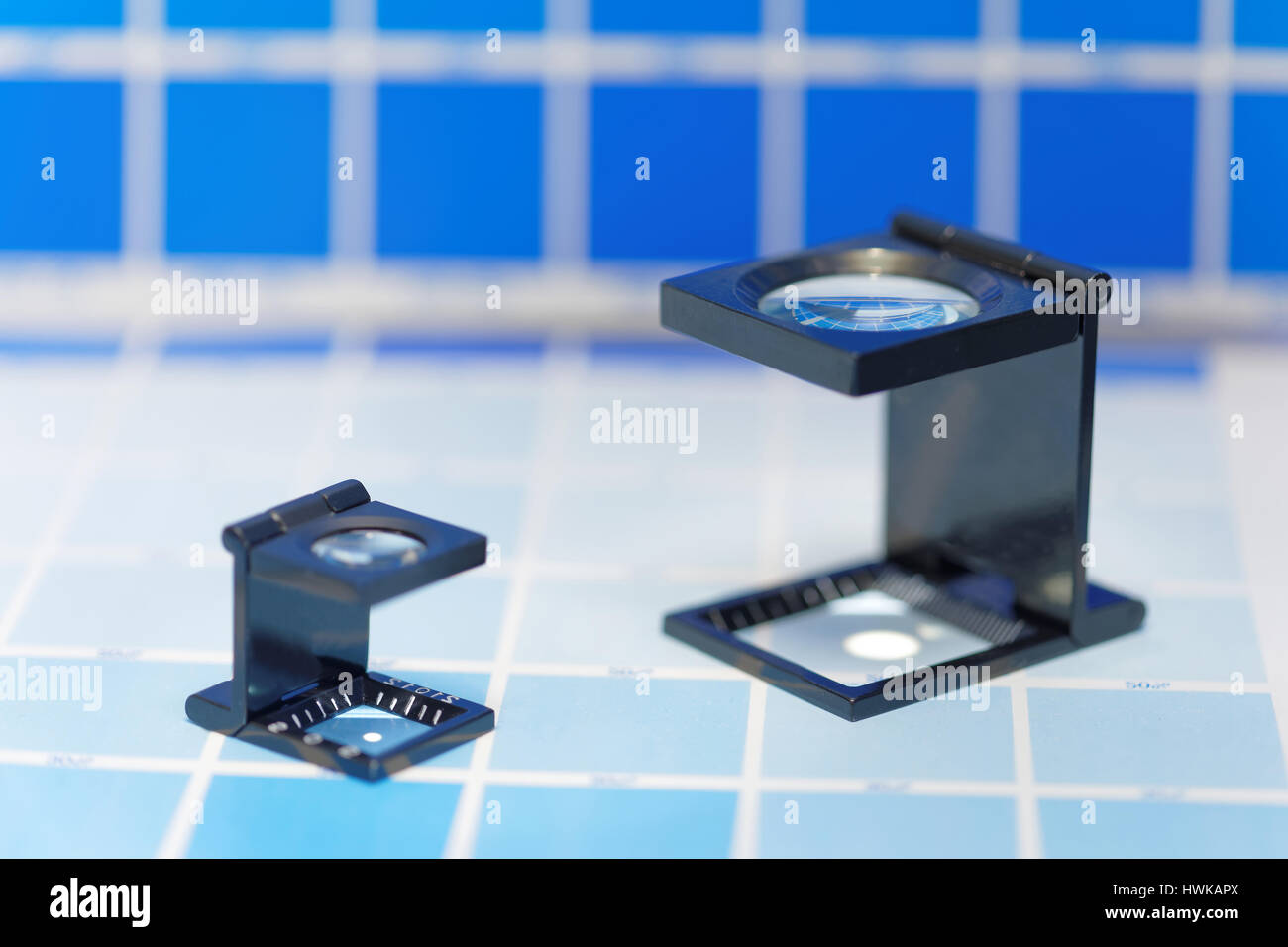 Two magnifier or printer's loupe sits on a cyan test sheet in a pre ...