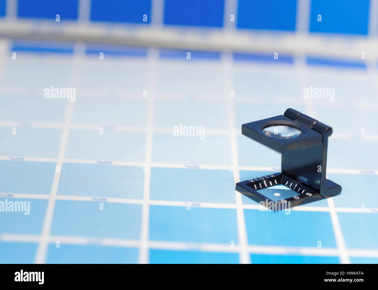 Magnifier or printer's loupe sits on a cyan test sheet in a pre-press ...