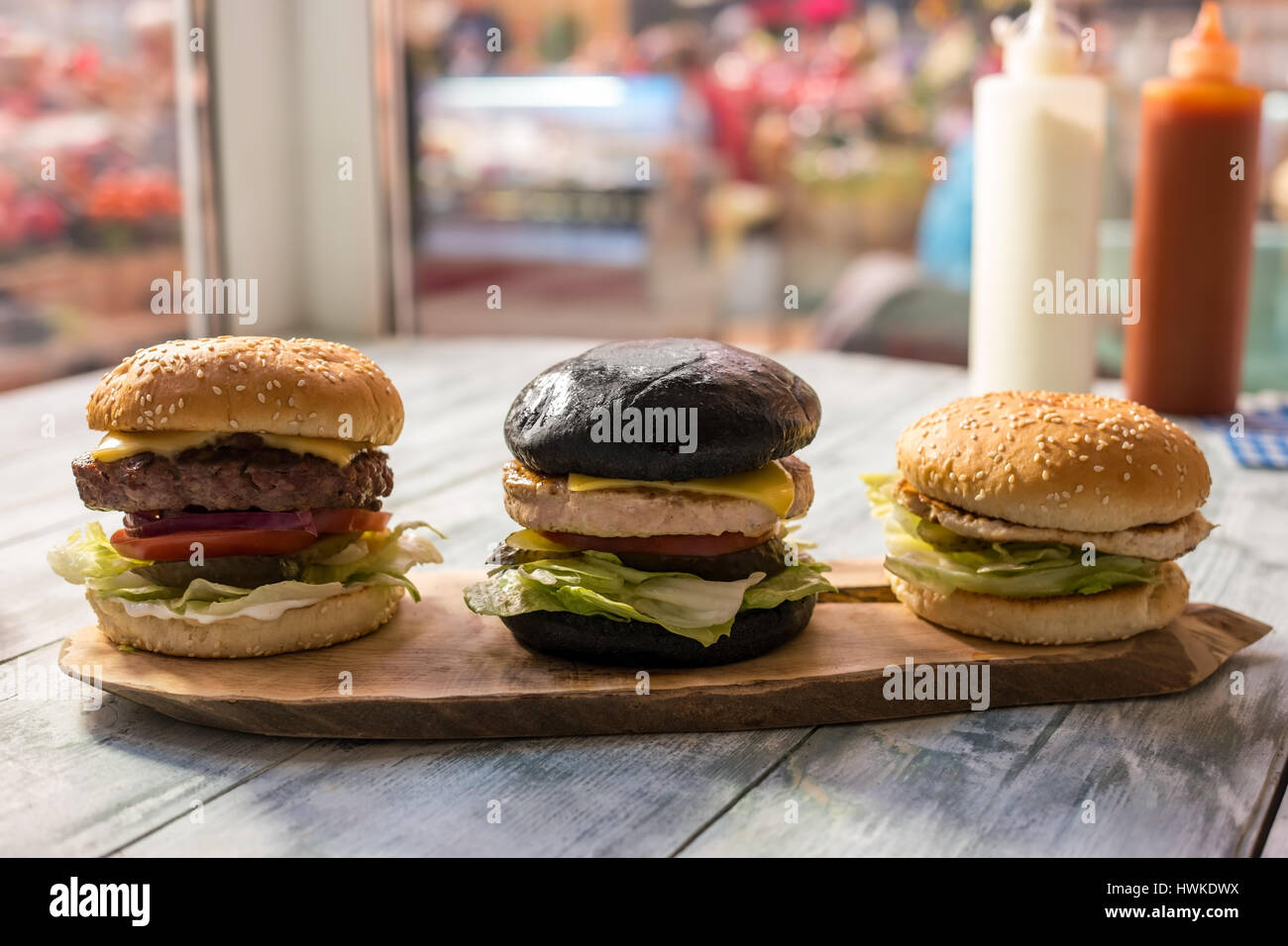 Three burgers on wooden board Stock Photo - Alamy