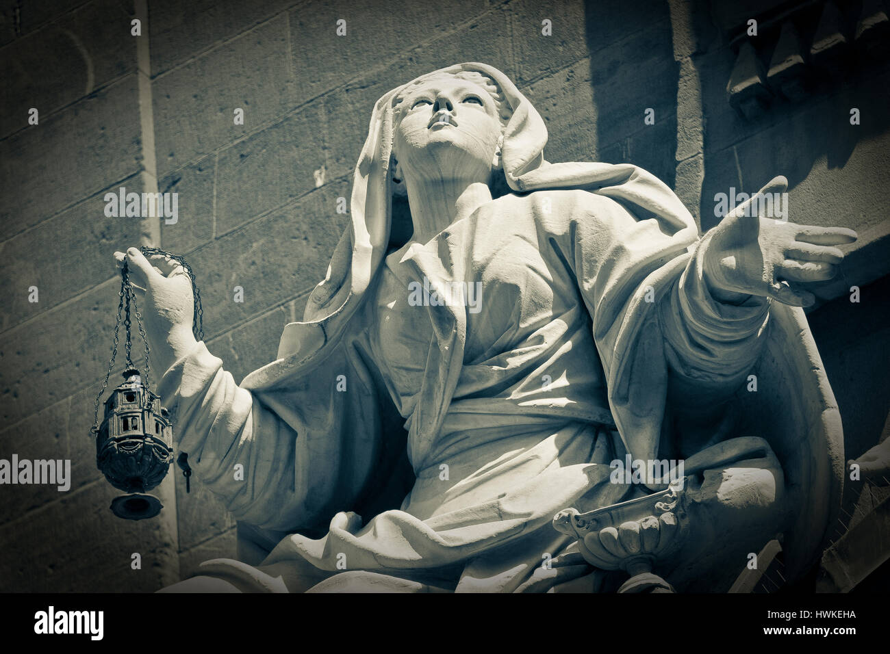Low angle view on beautiful stone sculpture of pious woman holding lamp ...
