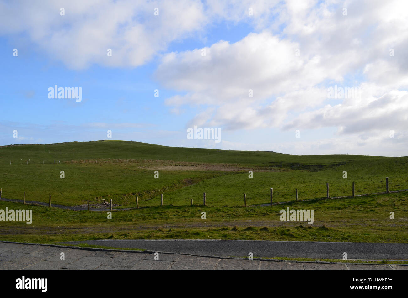 Ireland's green grassy field with fluffy white clouds over the field in ...
