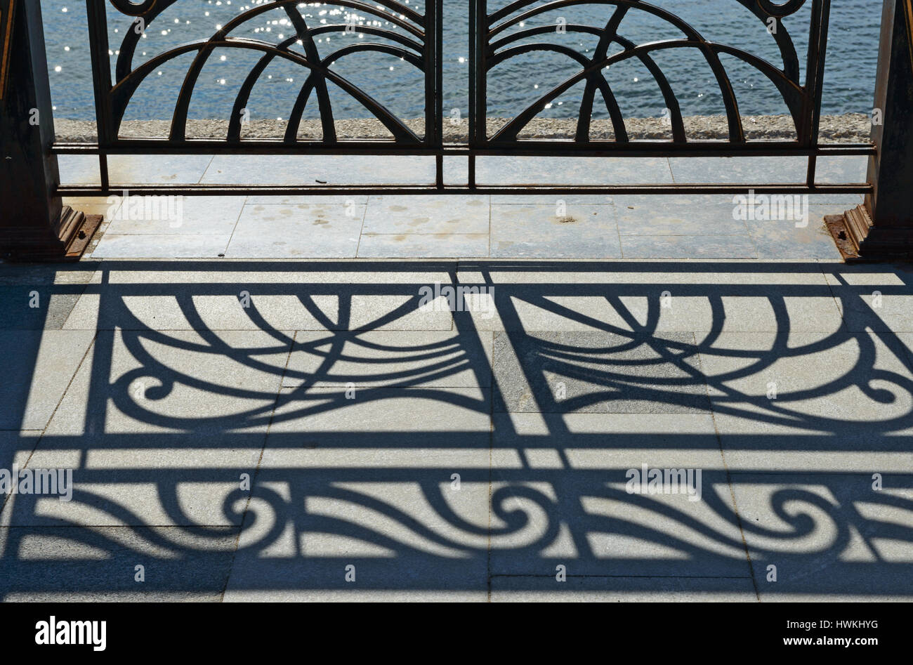 Openwork silhouette and shadow of forged iron railing in bright contre ...