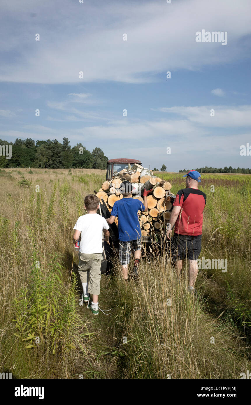Father and sons follow wagon filled with firewood through a trail in a ...