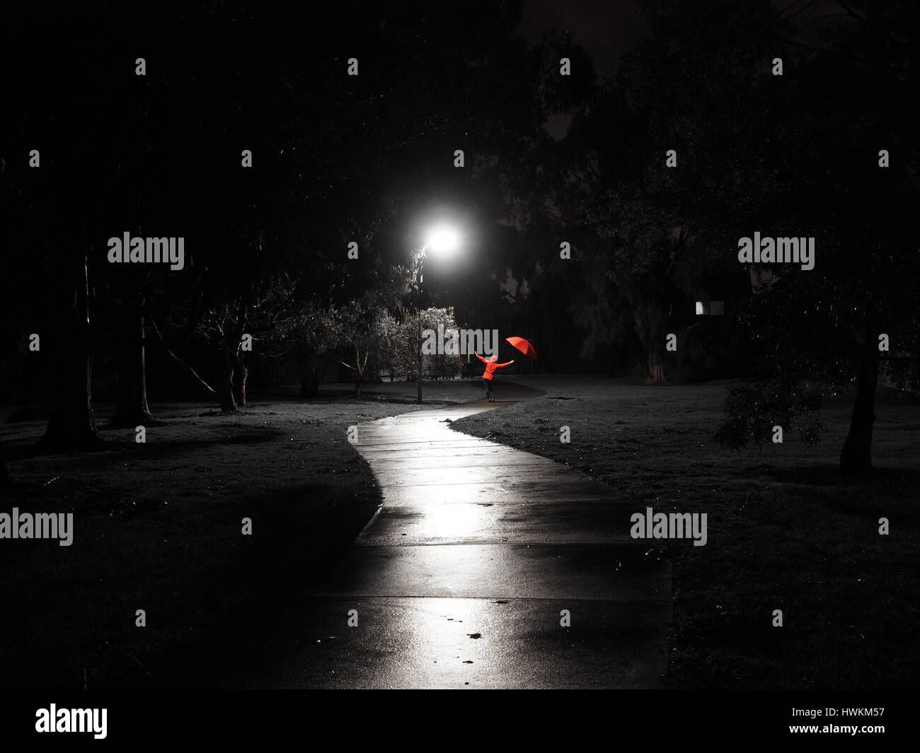Red female dancing with red umbrella at a creepy dark bike path lit by ...
