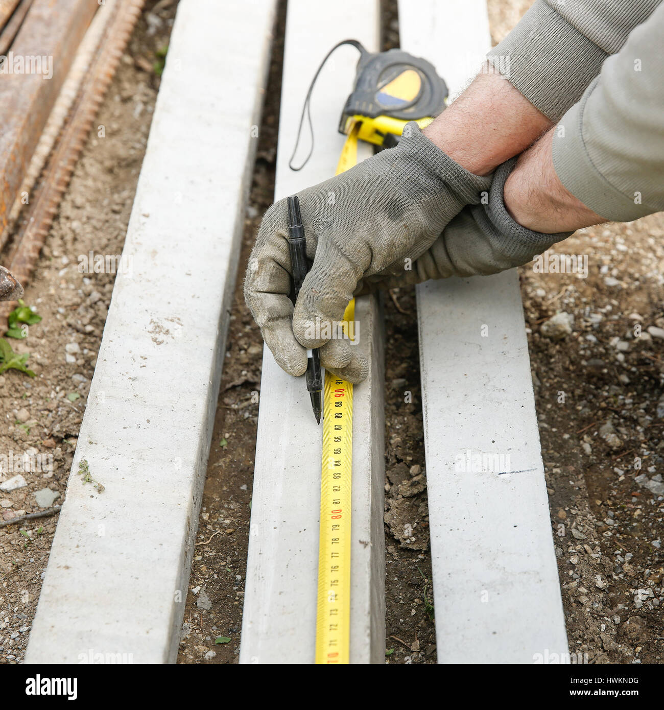 Construction worker measuring a reinforced concrete pillar for cutting ...