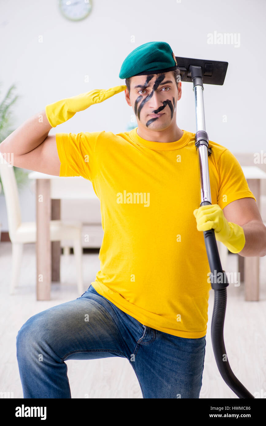 Funny man in military style cleaning the house Stock Photo - Alamy