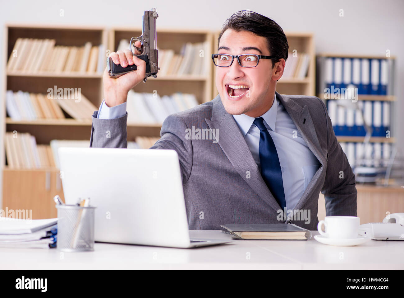 Funny businessman with gun in office Stock Photo - Alamy