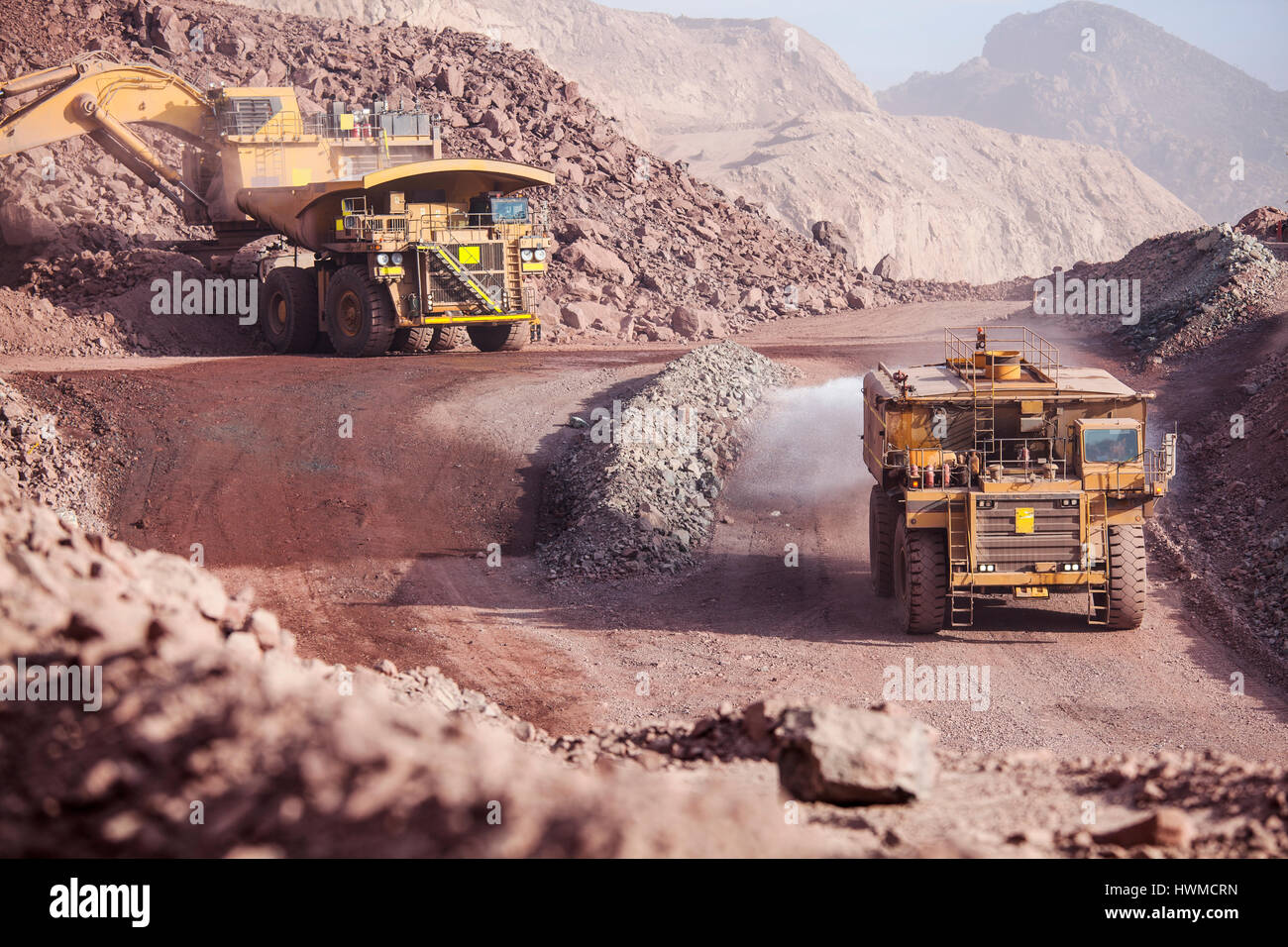 Loading of copper ore on very big dump-body truck and watering road ...