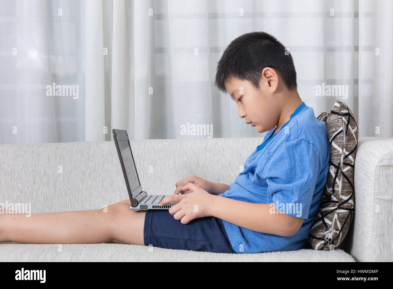 Asian Chinese little boy using laptop on the sofa in the living room at ...