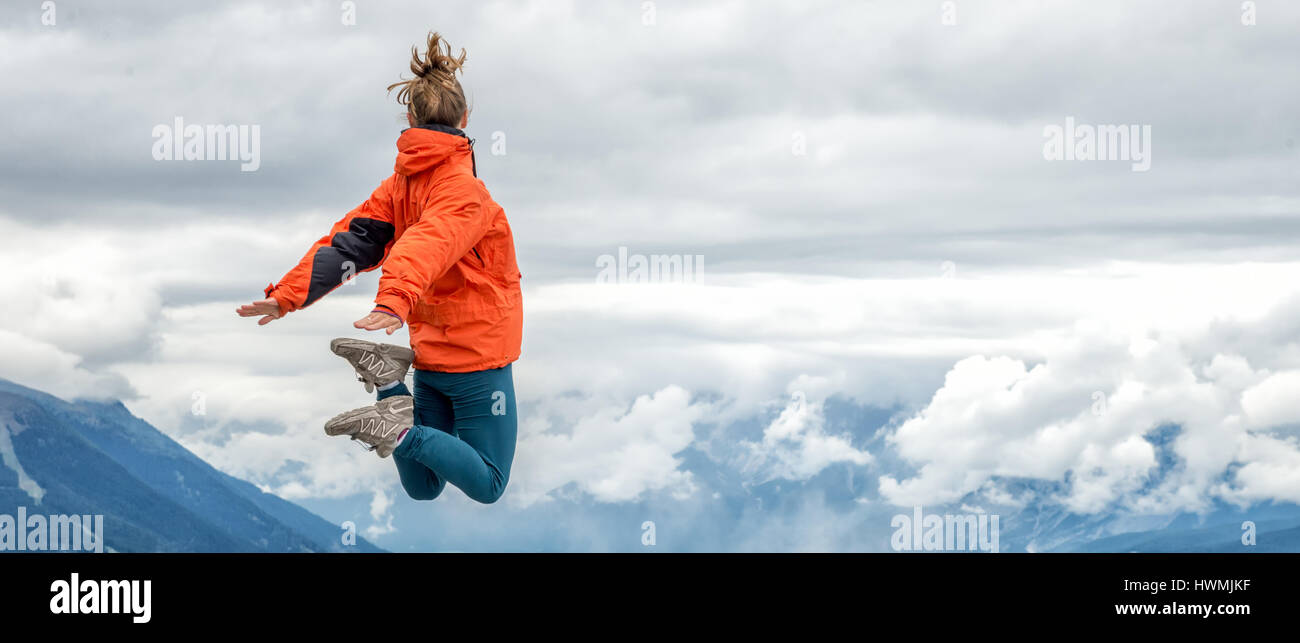 young woman jumping on top of the mountain Stock Photo - Alamy