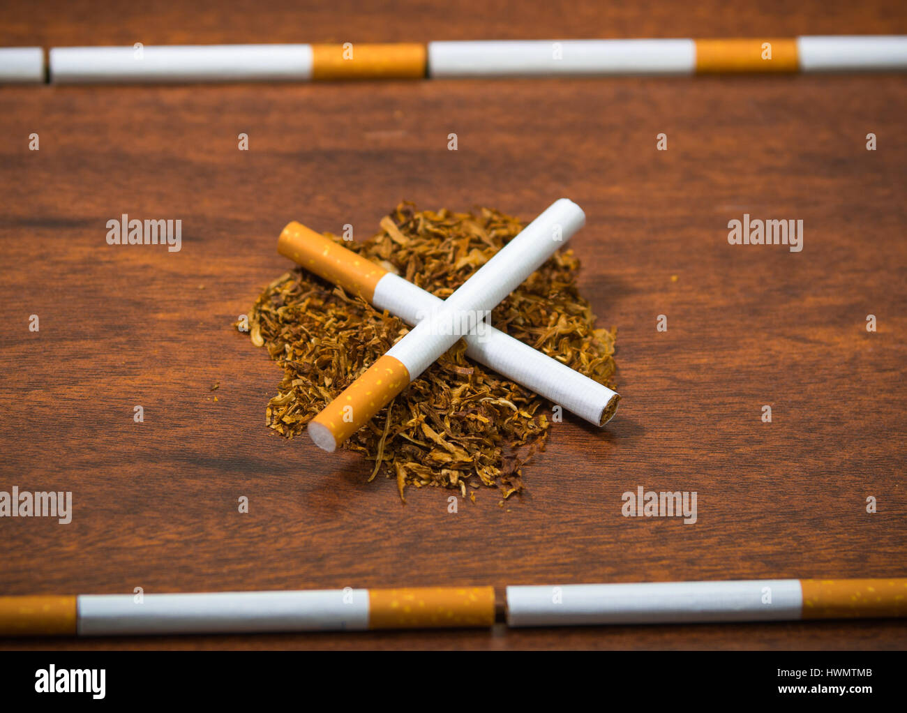 Cigarettes lying on wooden surface shaping into crossed lines, tobacco ...