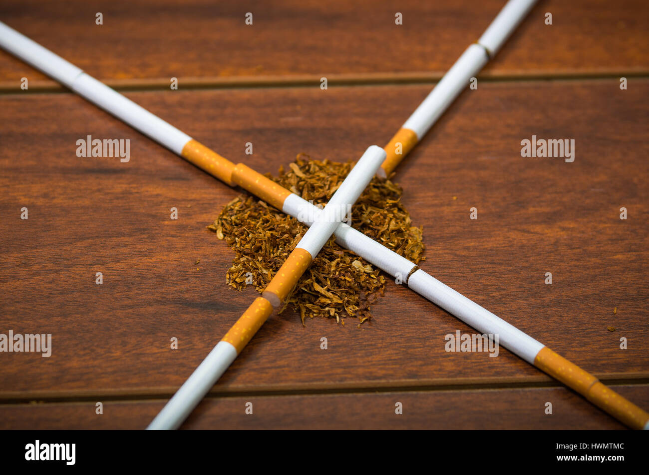 Cigarettes lying on wooden surface shaping into crossed lines, tobacco ...
