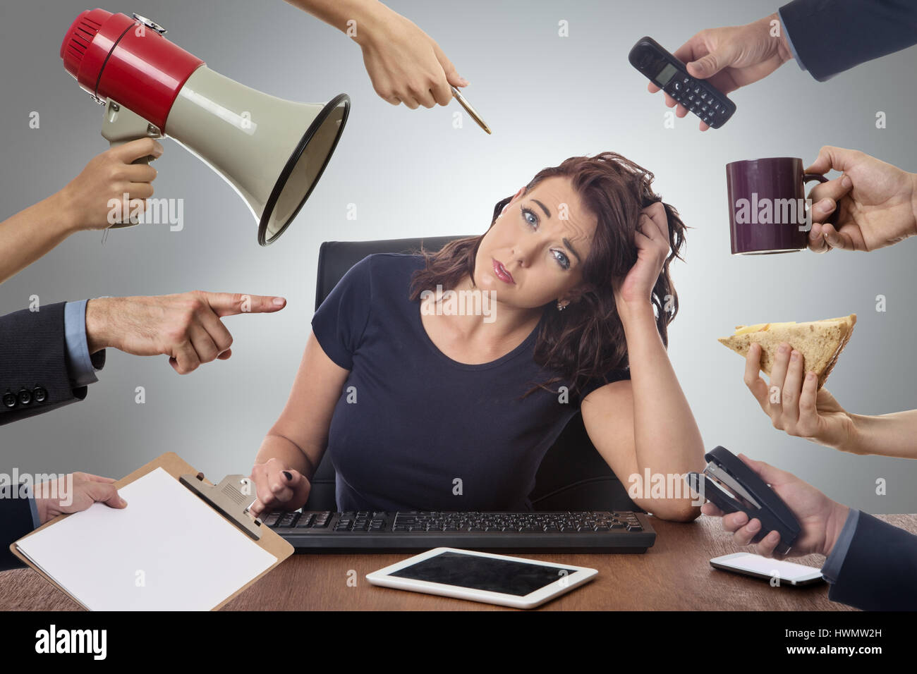 business woman sitting at desk surrounded by many hands holding objects ...