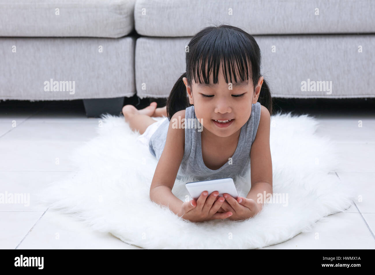 Happy Asian Chinese little girl playing phone on the floor in the ...