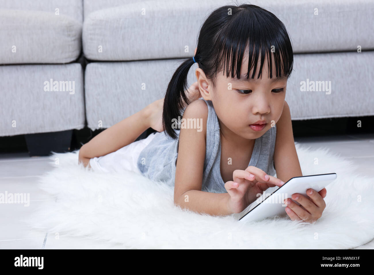 Asian Chinese little girl playing phone on the floor in the living room ...