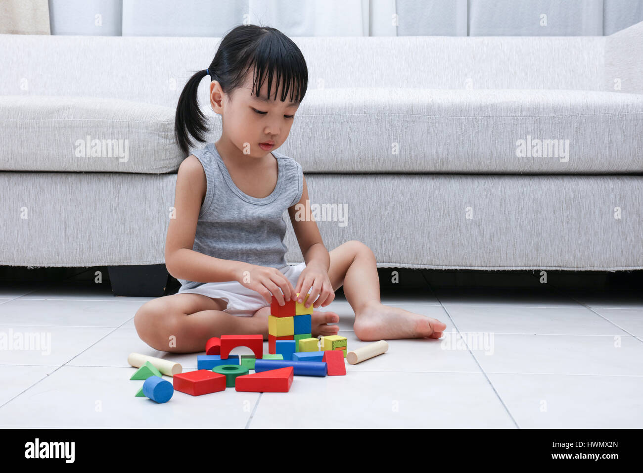 Asian Chinese little girl playing blocks on the floor in the living ...