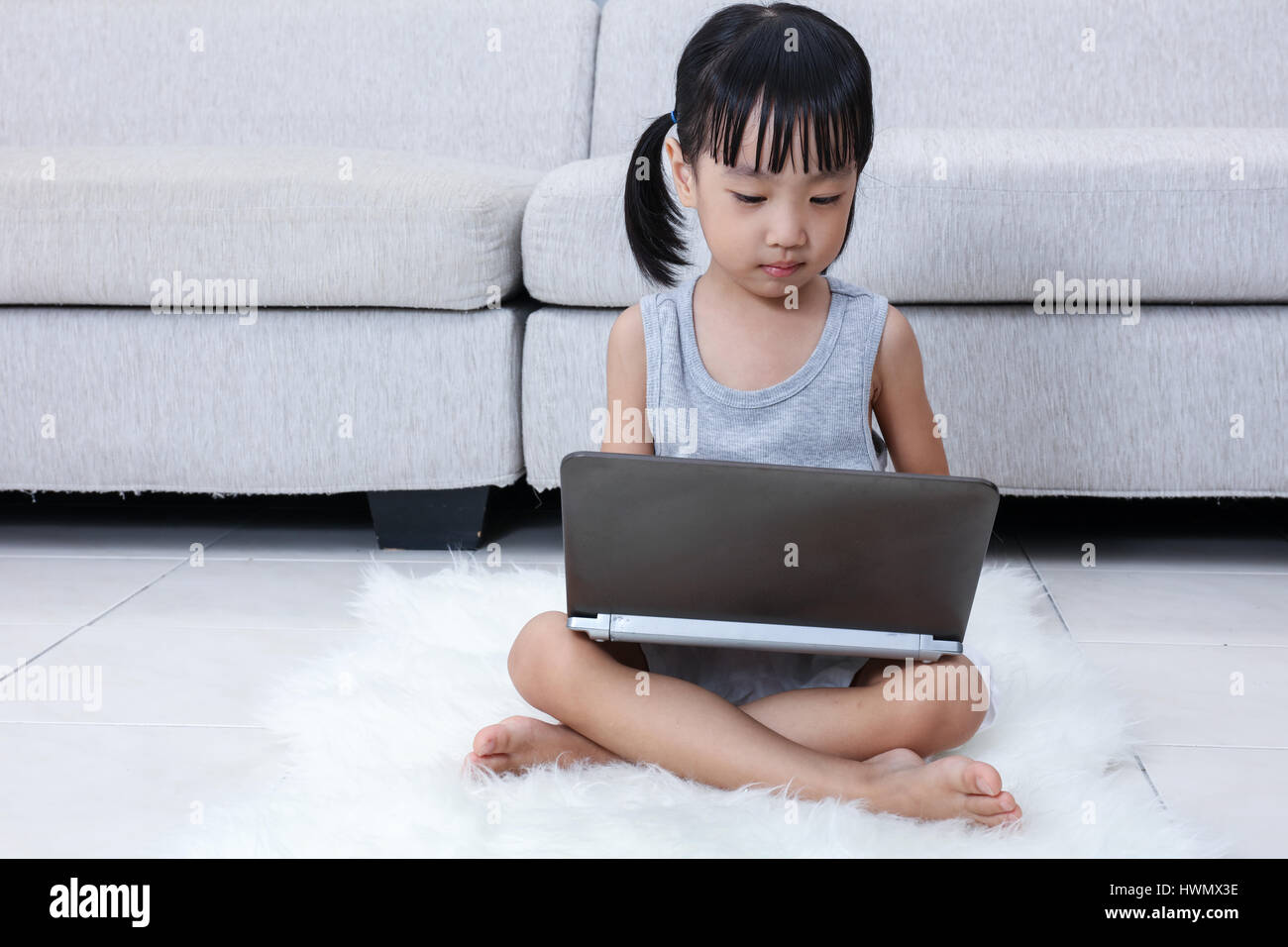 Asian Chinese little girl using laptop on the floor in the living room ...