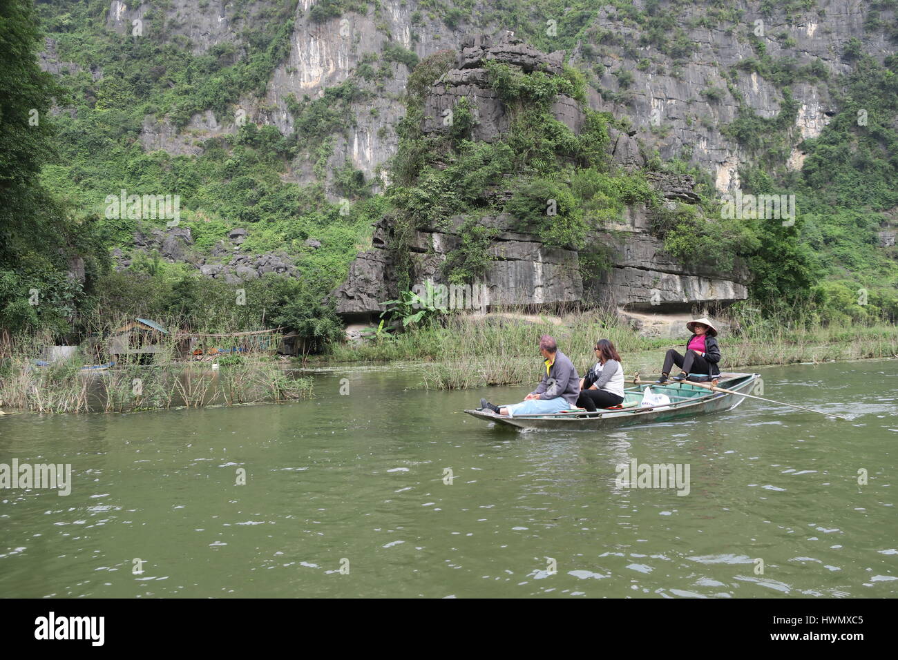A view from a boat. Rowing with the feet on the Tam Coc River in Ninh ...