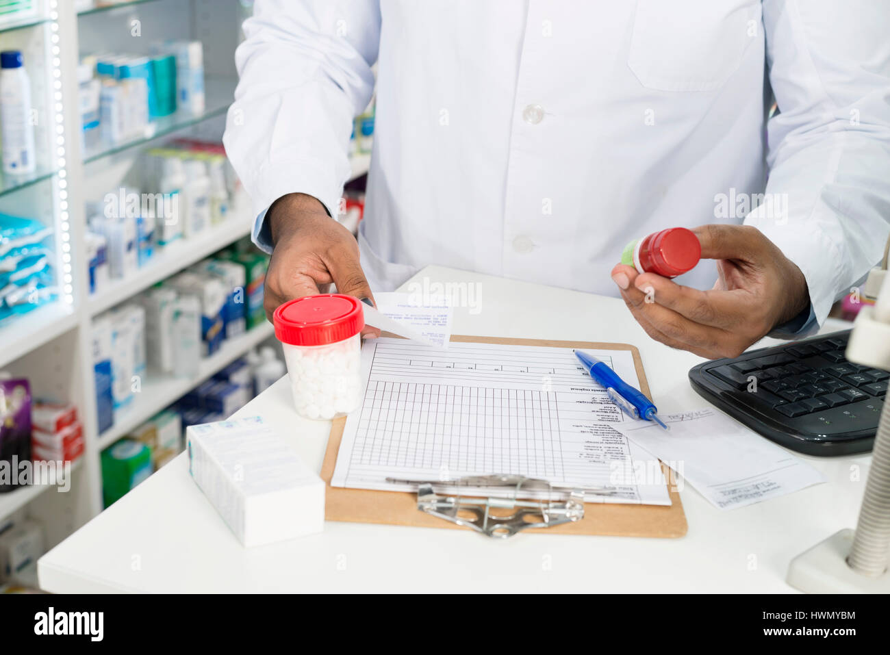 Pharmacist With Pill Bottles And Clipboard At Counter Stock Photo - Alamy