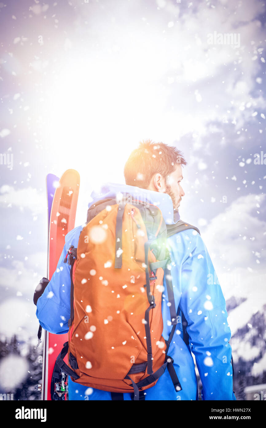 Rear view of skier standing with ski on snow covered mountains Stock ...