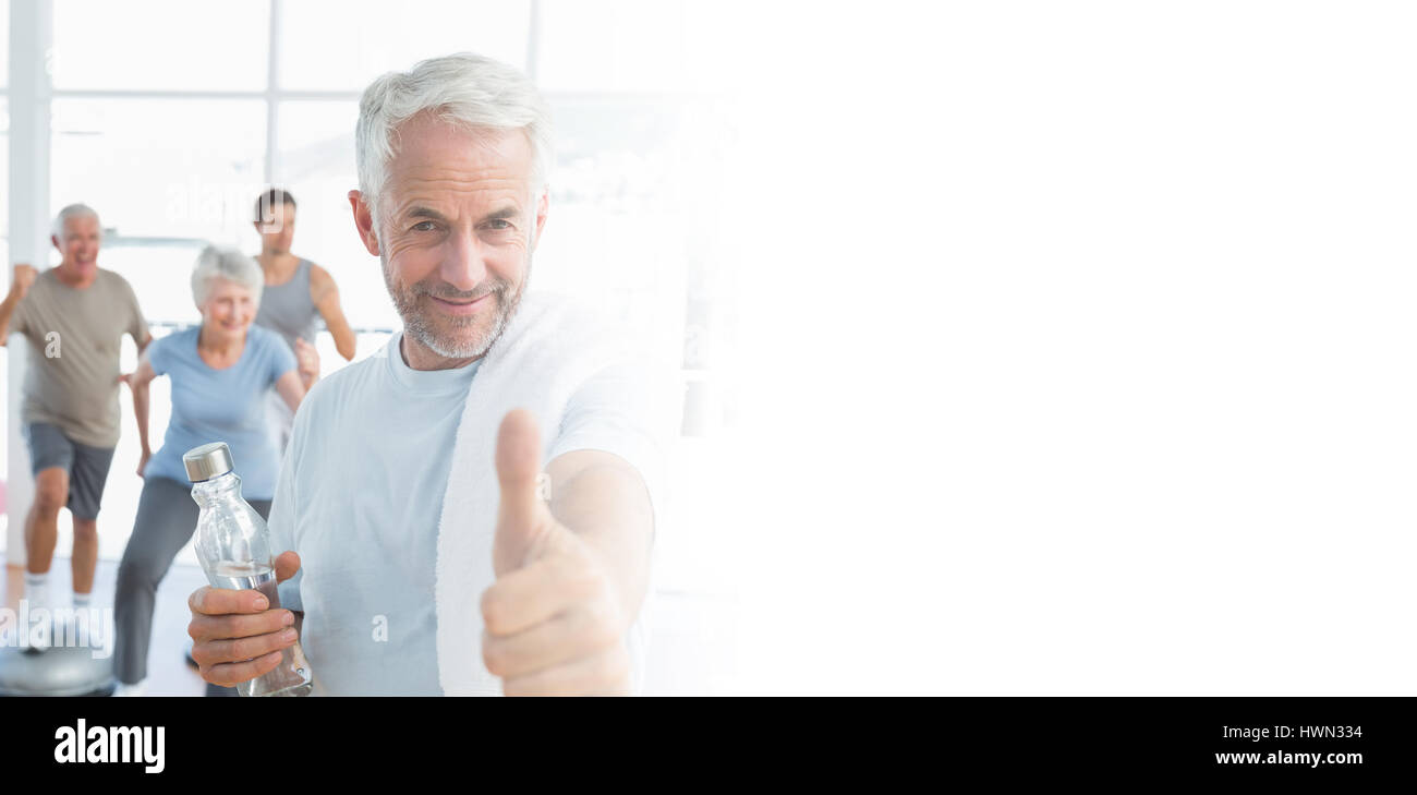 Man showing thumbs up sign with people exercising in background at ...