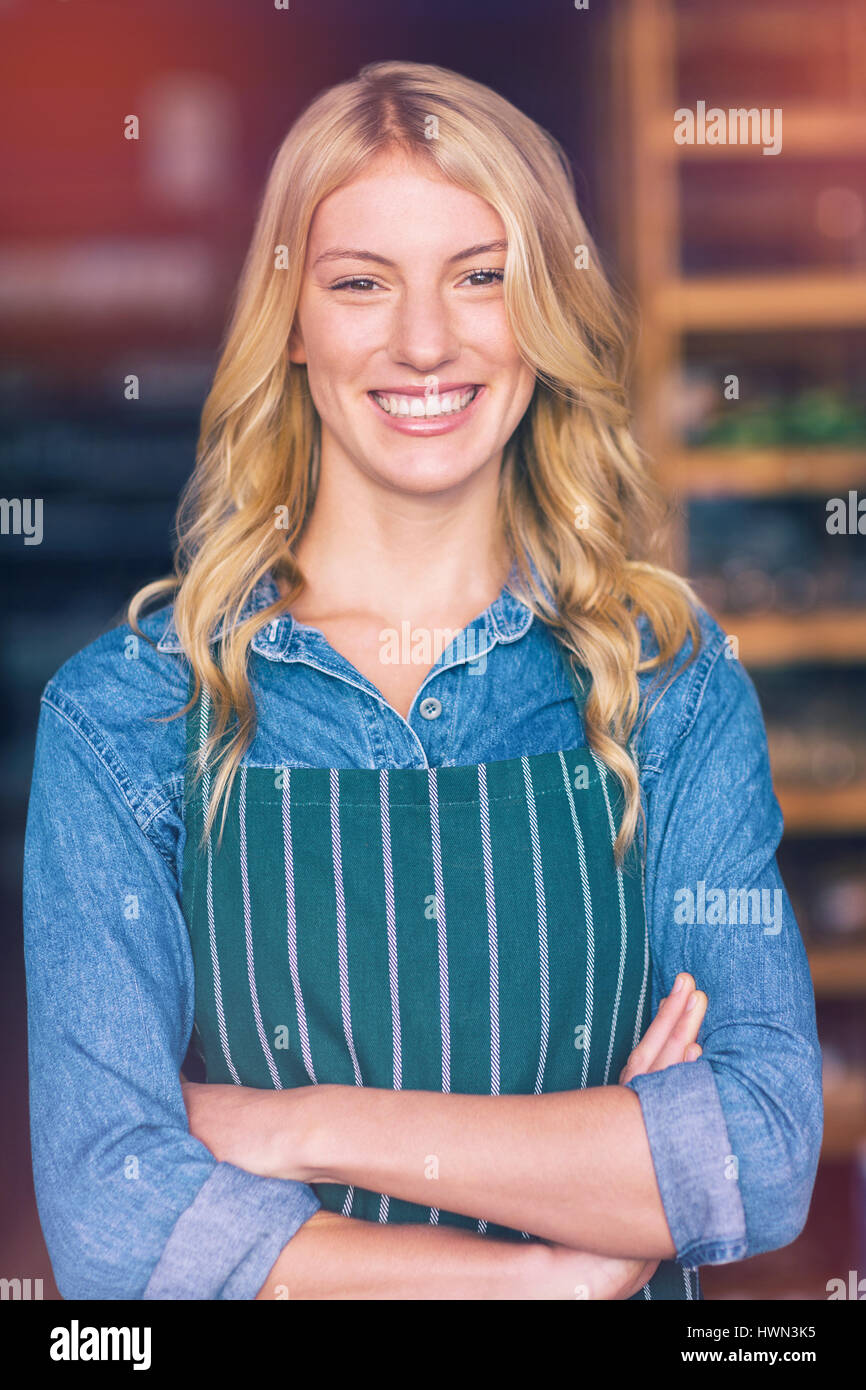 Portrait of smiling female staff standing with arms crossed in super ...