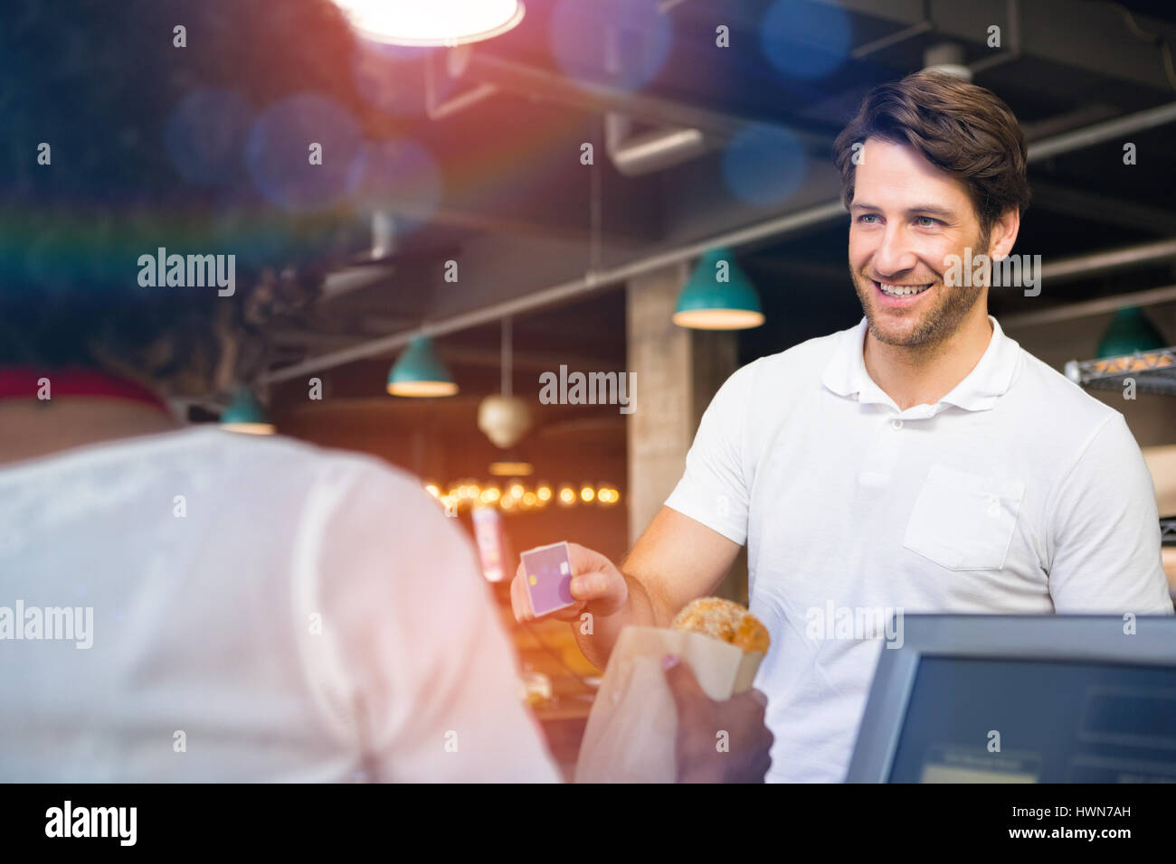 Graphic image of flare against happy customer paying by credit card for ...