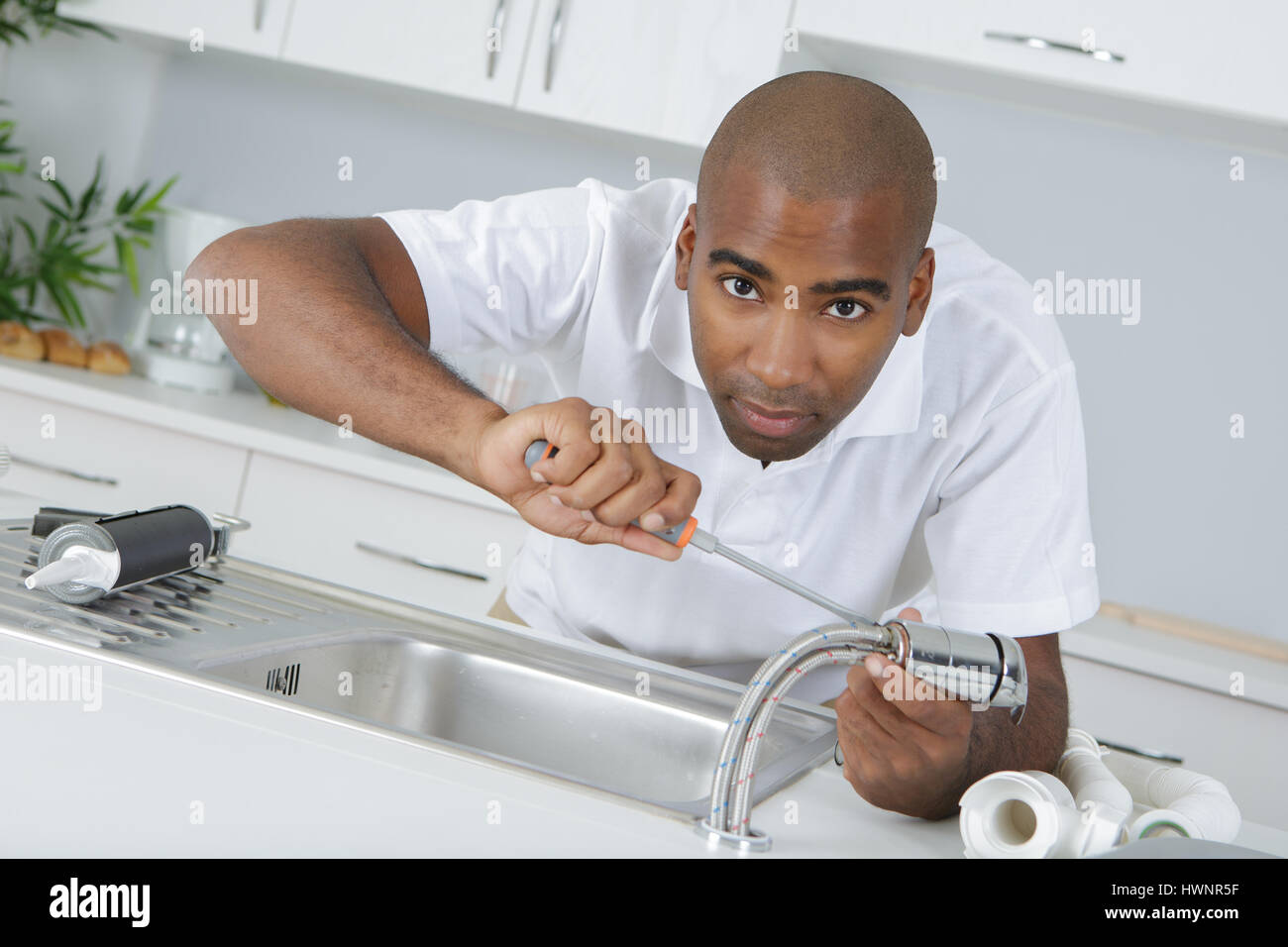 Plumber working on kitchen faucet Stock Photo - Alamy