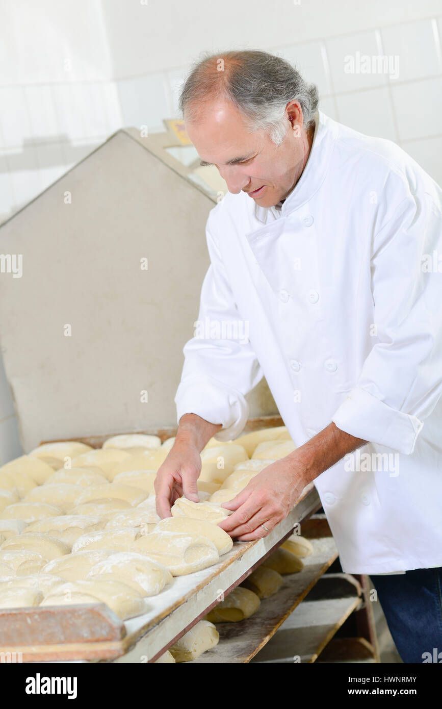 Baker preparing batch of bread rolls Stock Photo - Alamy