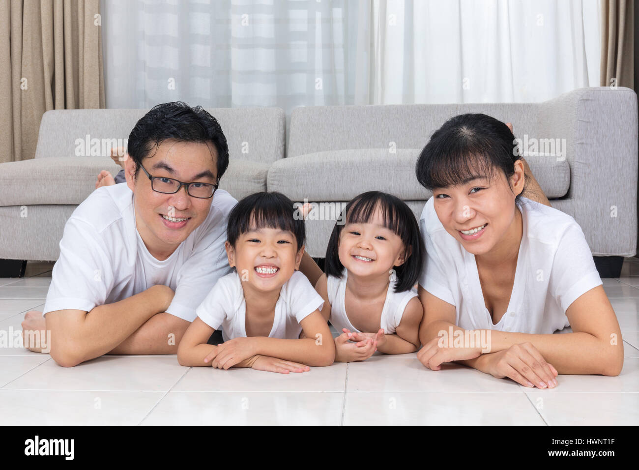 Happy Asian Chinese parents and daughters lying on the floor in the ...