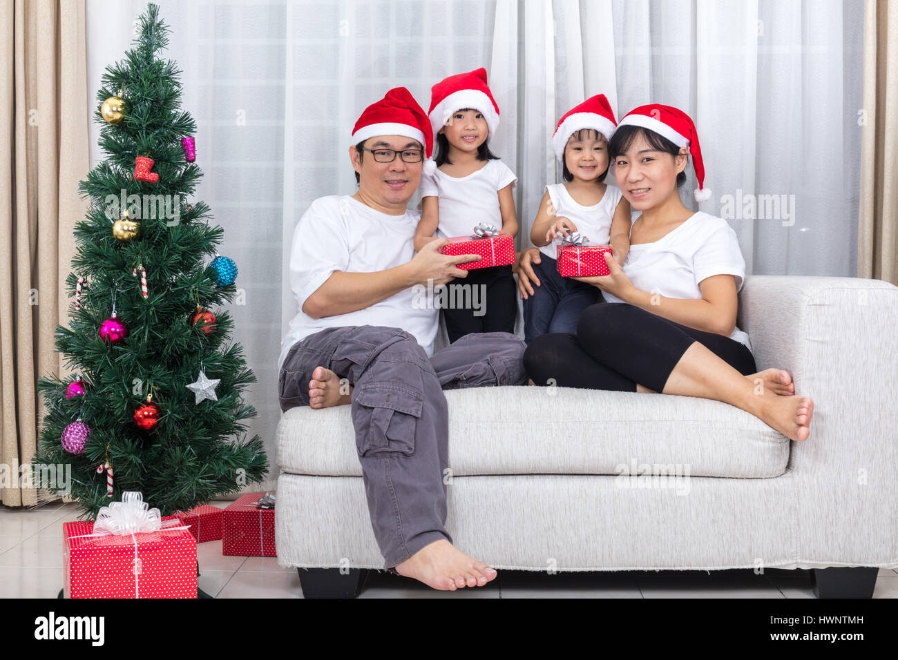 Happy Asian Chinese family wearing Santa Claus hat exchange Christmas ...