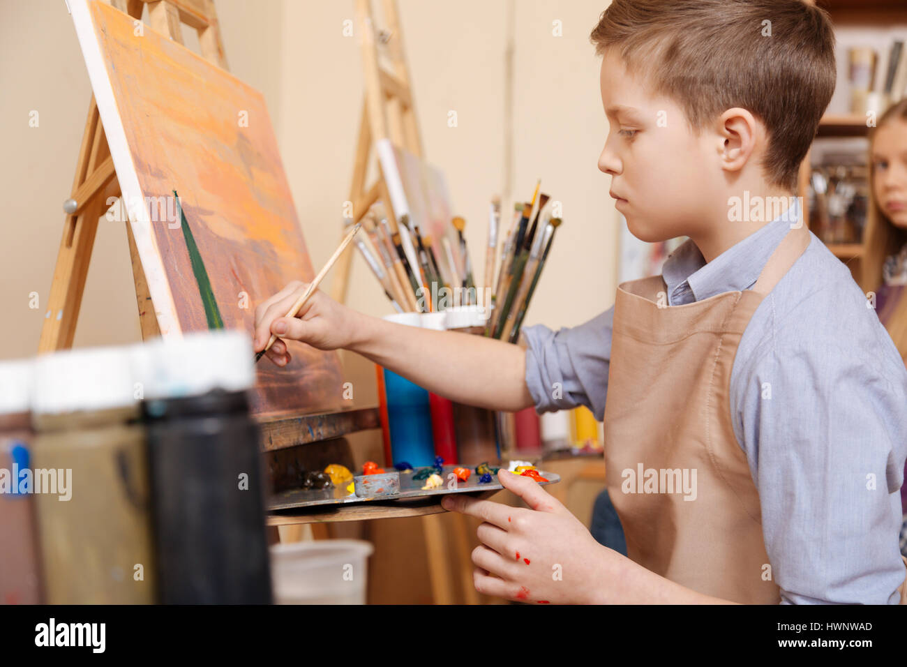Full of concentration. Attentive talented young boy sitting in the art ...